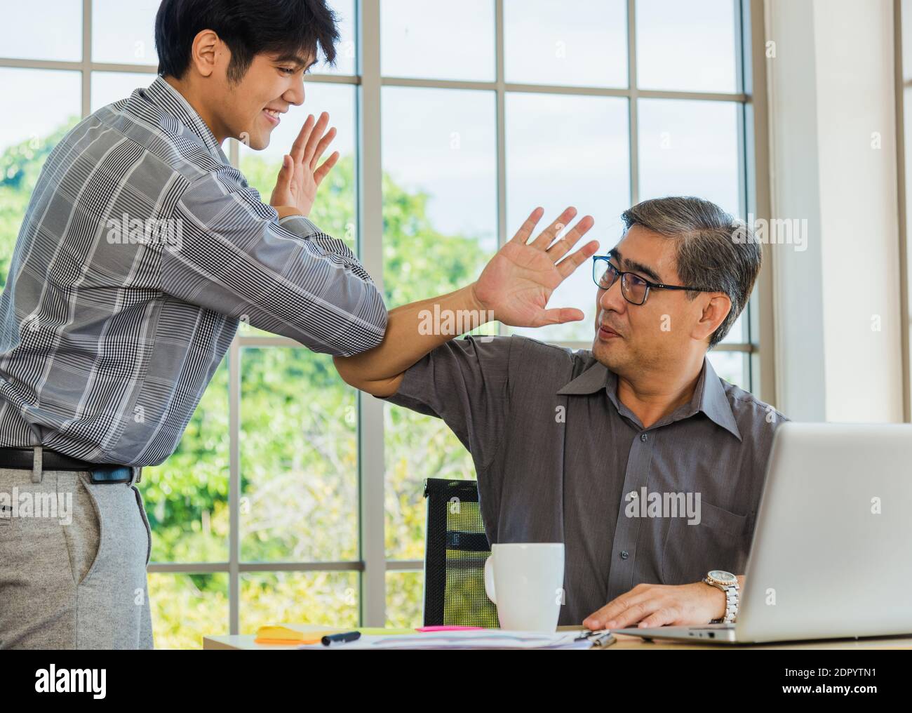Asian senior and young business man greeting each other in the office ...