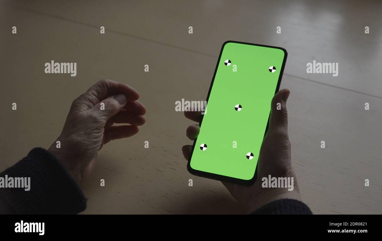old female hands holding smartphone with green screen over wood vintage ...