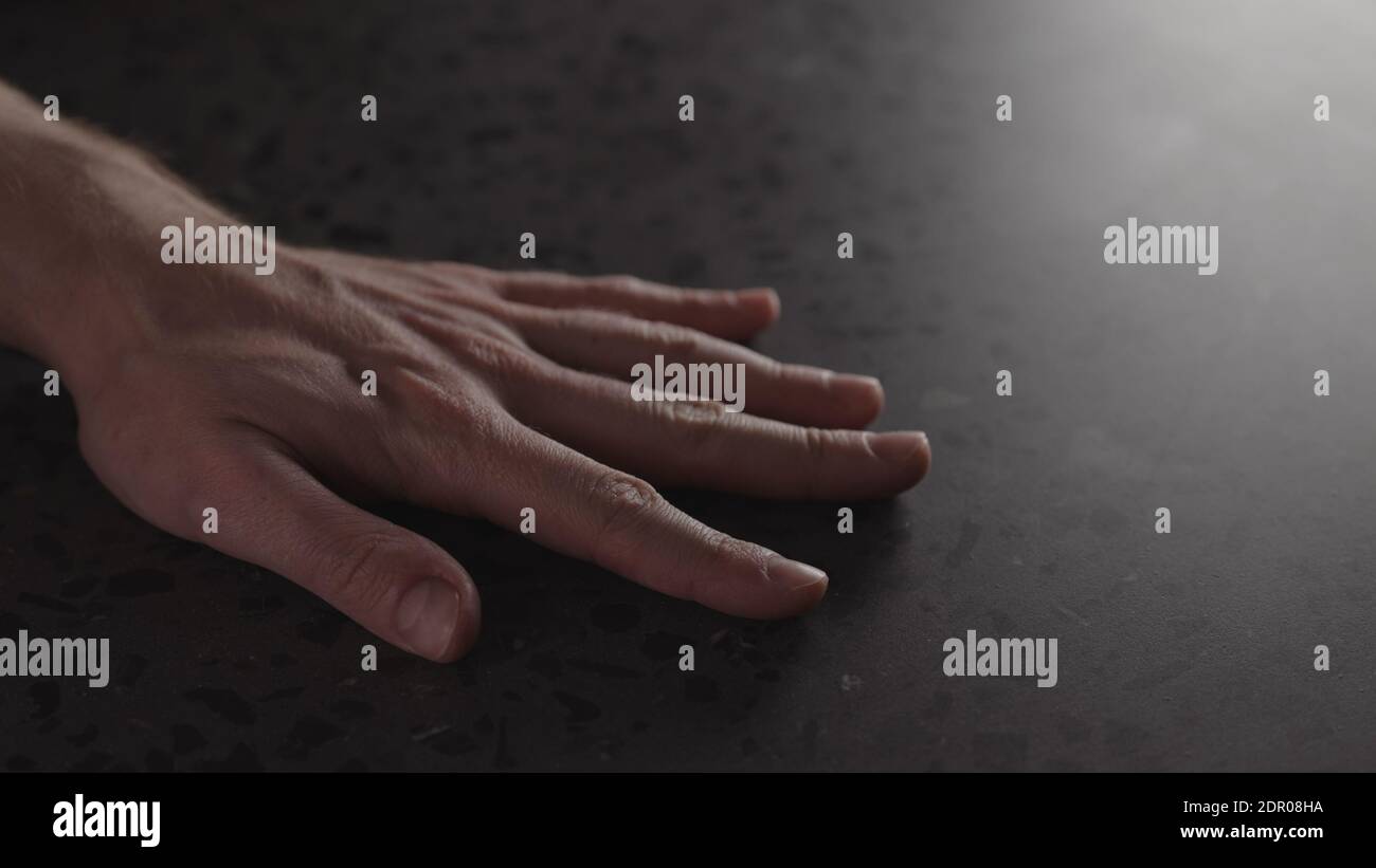 young man hand finger tap on terrazzo countertop with dim light , wide ...