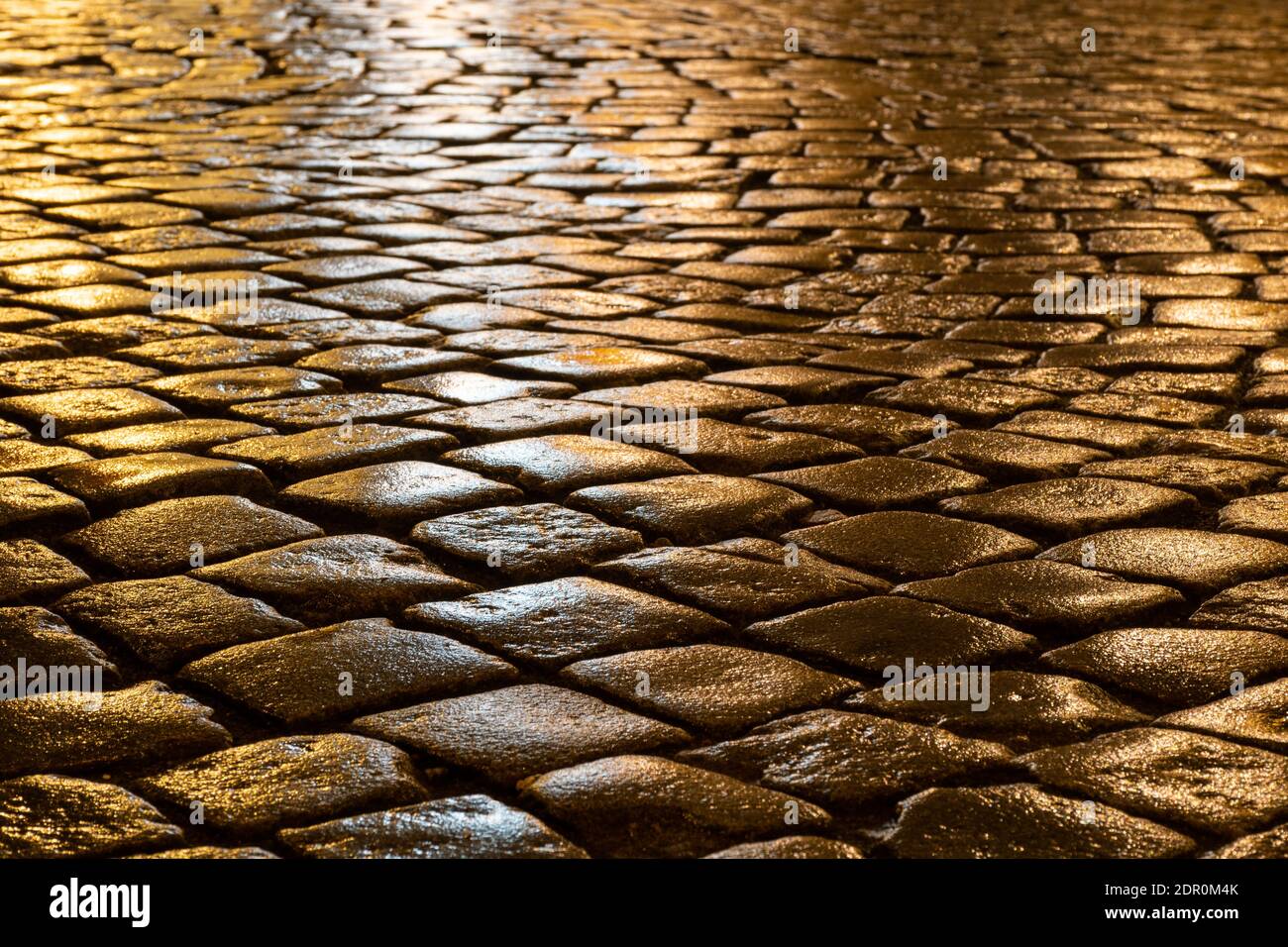 Wet cobblestones at night after rain on a street or road surface ...