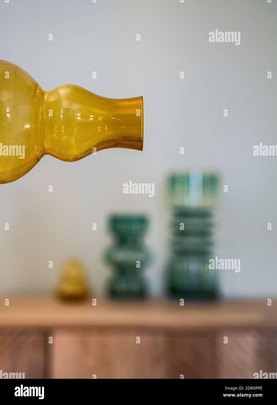Bottleneck of yellow transparent bottle with few vases at the blurred ...