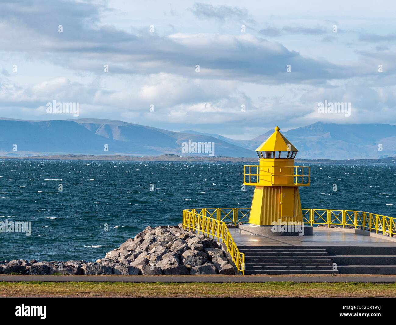 Yellow lighthouse tower on stone breakwater, entrance to Reykjavik port ...