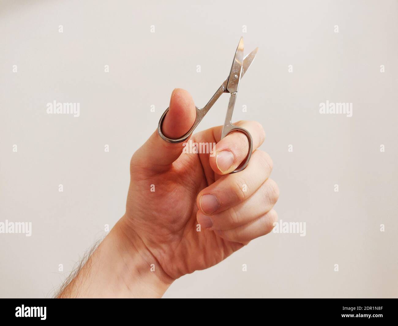 A closeup of a hand holding scissors on a white background Stock Photo ...