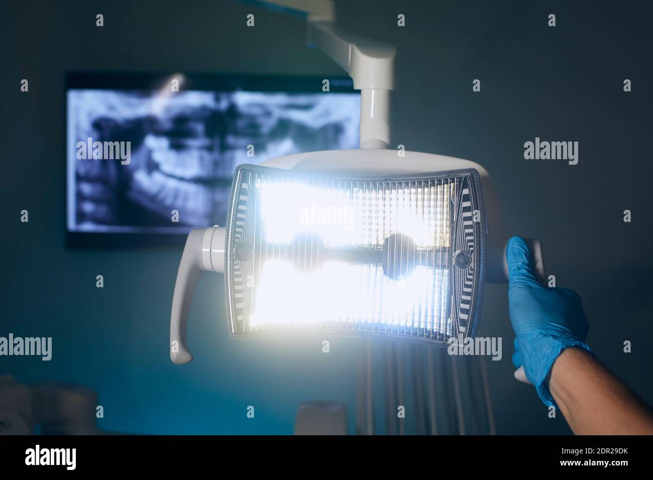 Modern dental surgery. Dentist adjusting lamp against x-ray of teeth in ...
