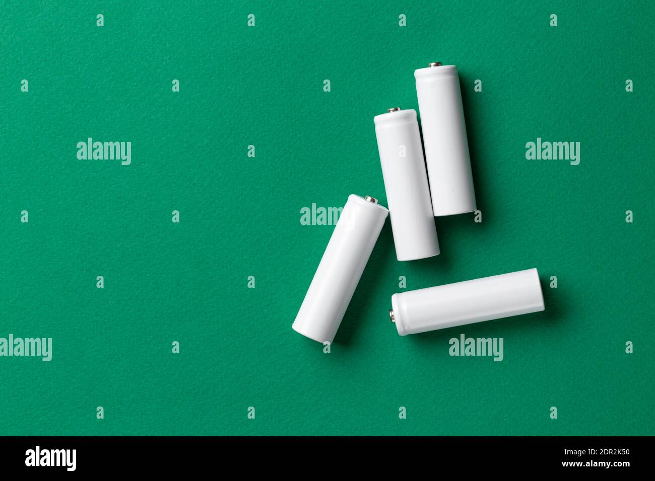 Rechargeable AAA batteries in white on a green background. Place for ...
