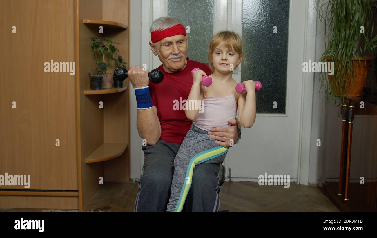 Granddaughter and mature grandfather in sportswear making sports ...