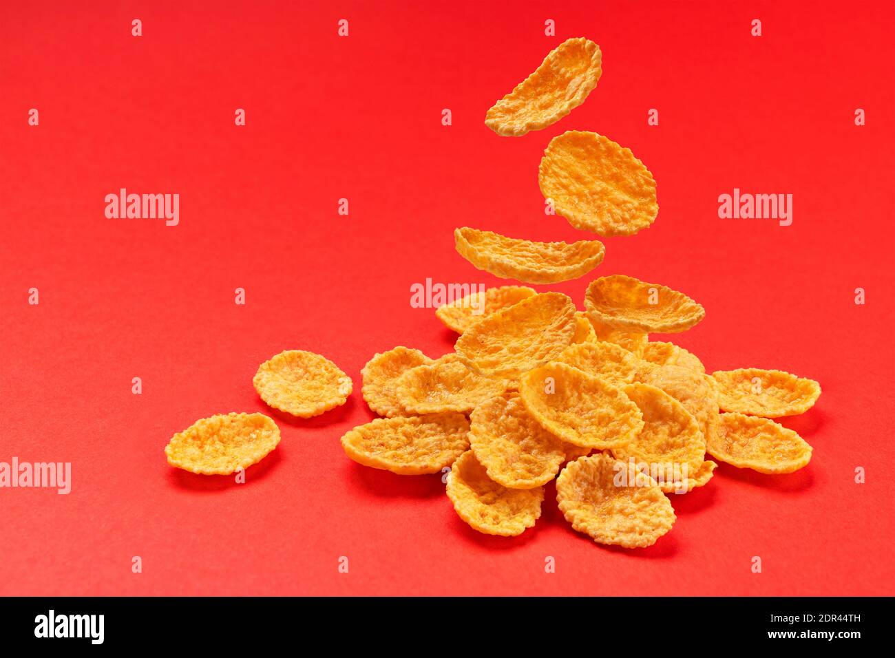 Falling corn flakes isolated on red color background, full depth of ...