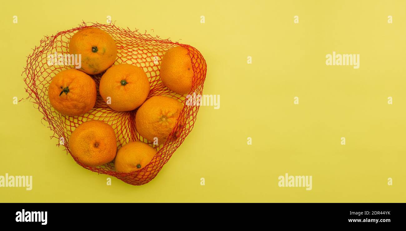 Tangerines in an open package isolated on a yellow background with copy ...