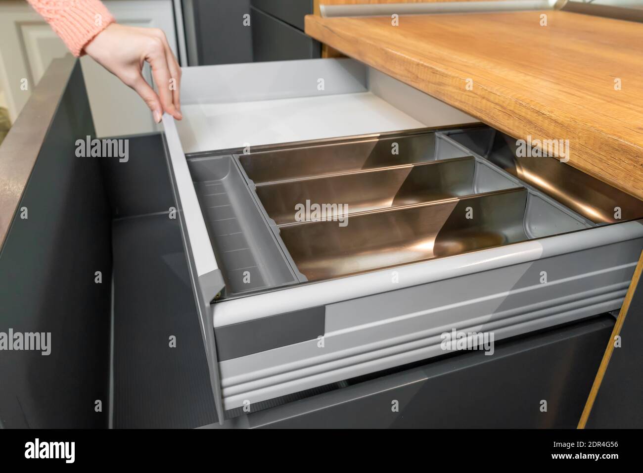 Woman's hand opens a kitchen drawer with an empty Cutlery tray. Two ...