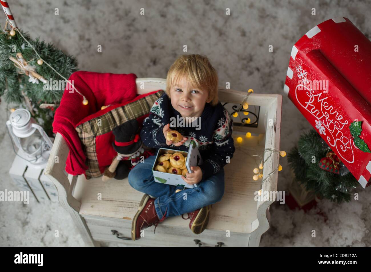 Beautiful child, blond toddler boy, eating cookies, sitting on a bench ...