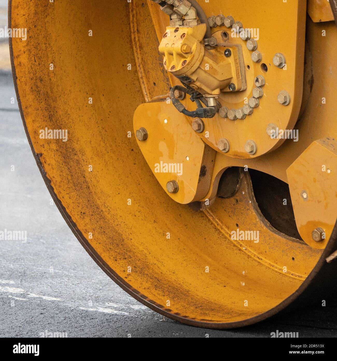 Steam billows up from hot asphalt being rolled during road paving work ...