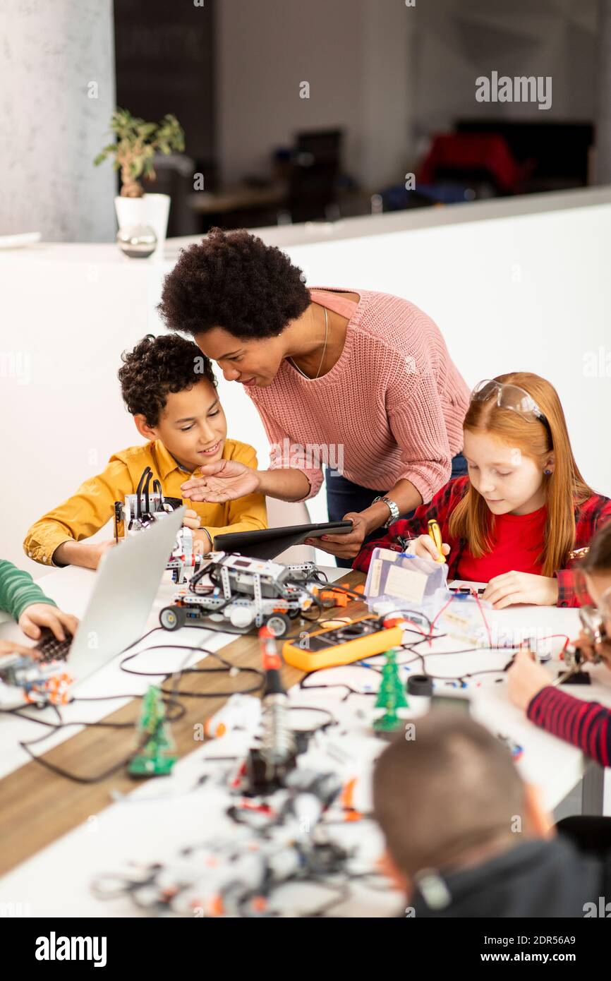 Smily African American female science teacher with group of kids ...