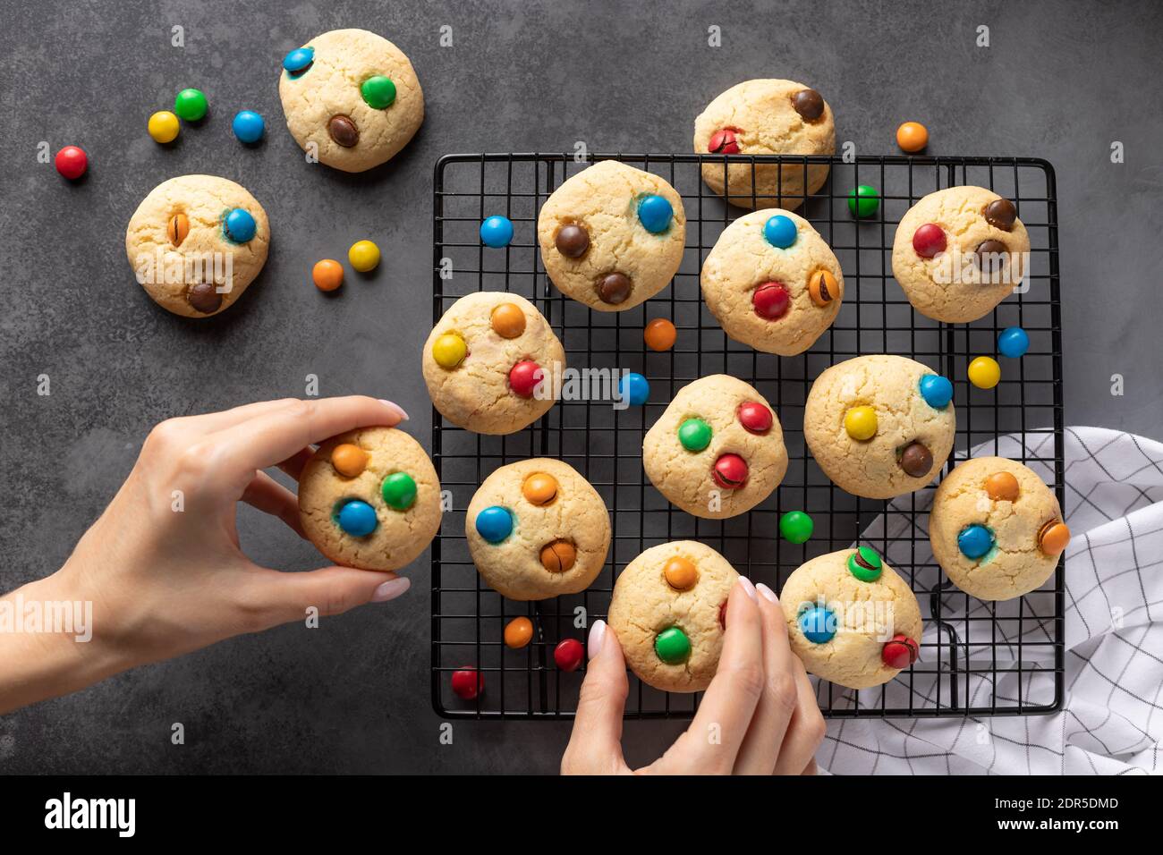 female hands holding cookies with colorful candies on dark background ...