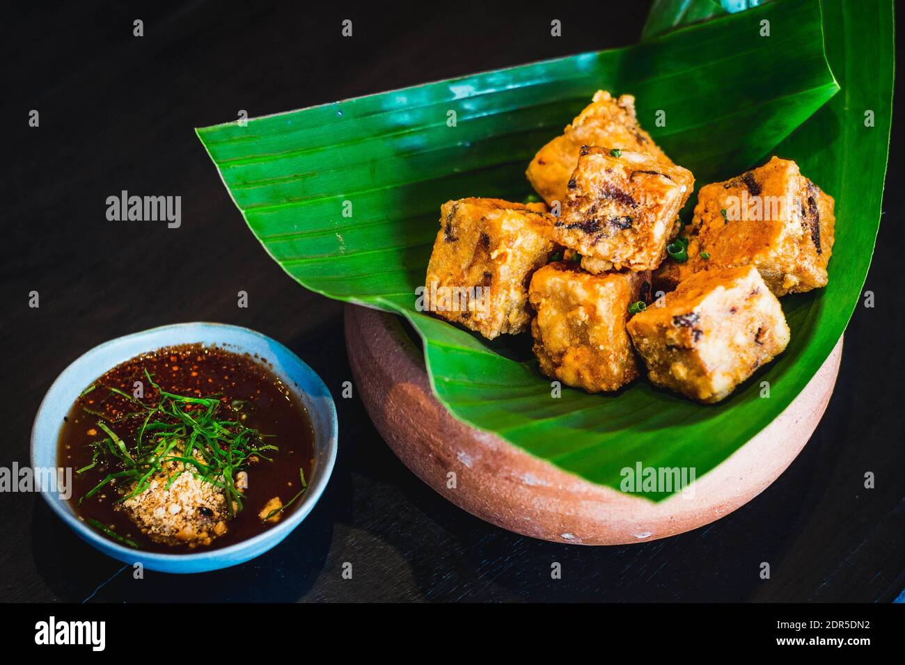 an appetizer of deep fried tofu cubes served in banana leaf with a ...