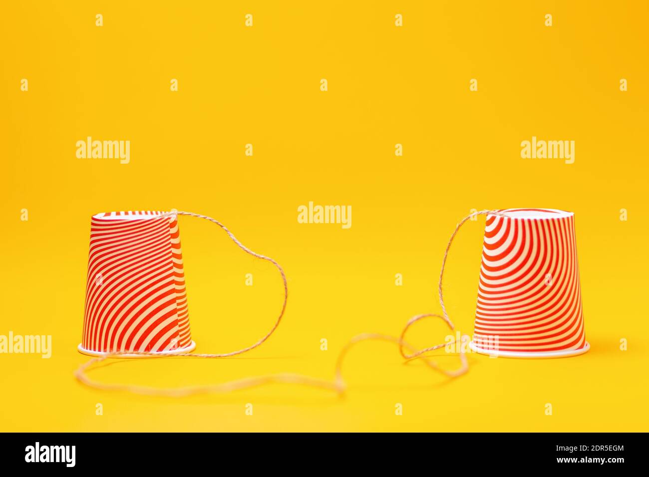 Two red paper cups connected by a long tangled string. Children's ...