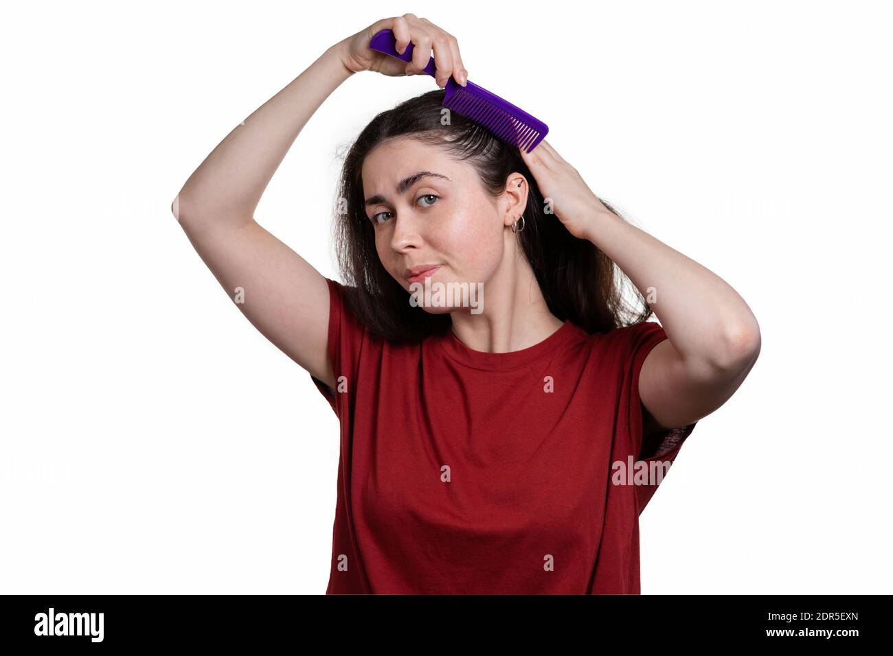 Portrait of a young woman in sad mood combing her hair, looking at the ...