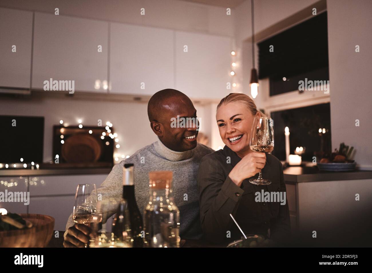 Laughing couple sitting at a dining table during a candlelit dinner ...