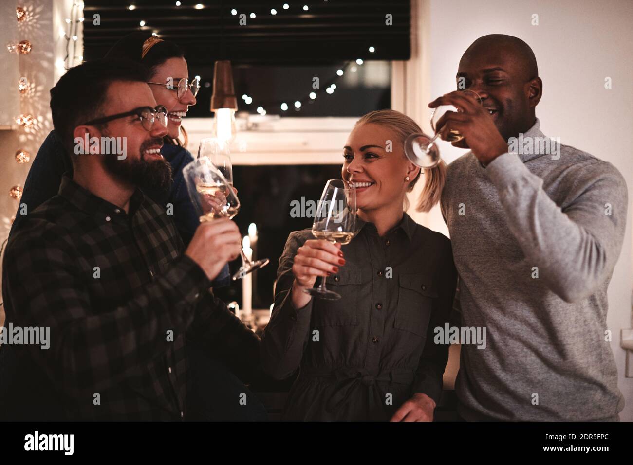 Two diverse young couples talking and laughing together over wine while ...