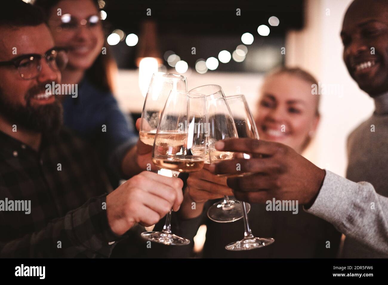 Closeup of a smiling group of diverse friends toasting each other with ...