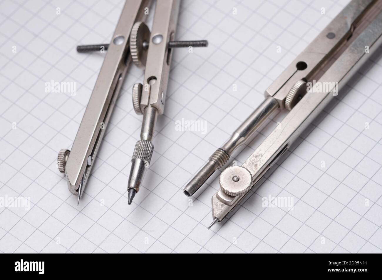 Metal drawing or drafting compass on blank white piece of paper ...