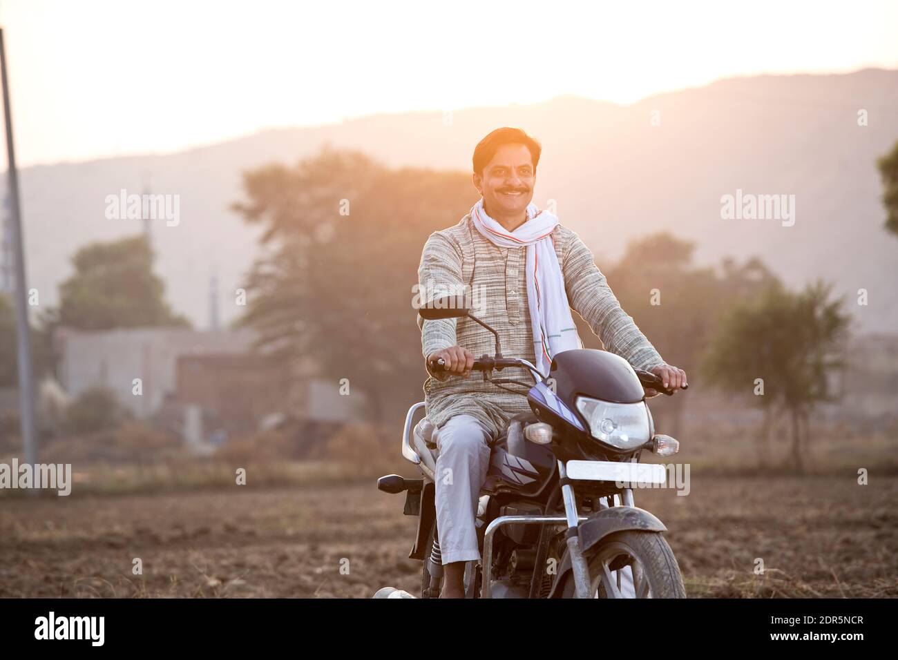 Happy rural Indian man riding on motorcycle in village Stock Photo - Alamy