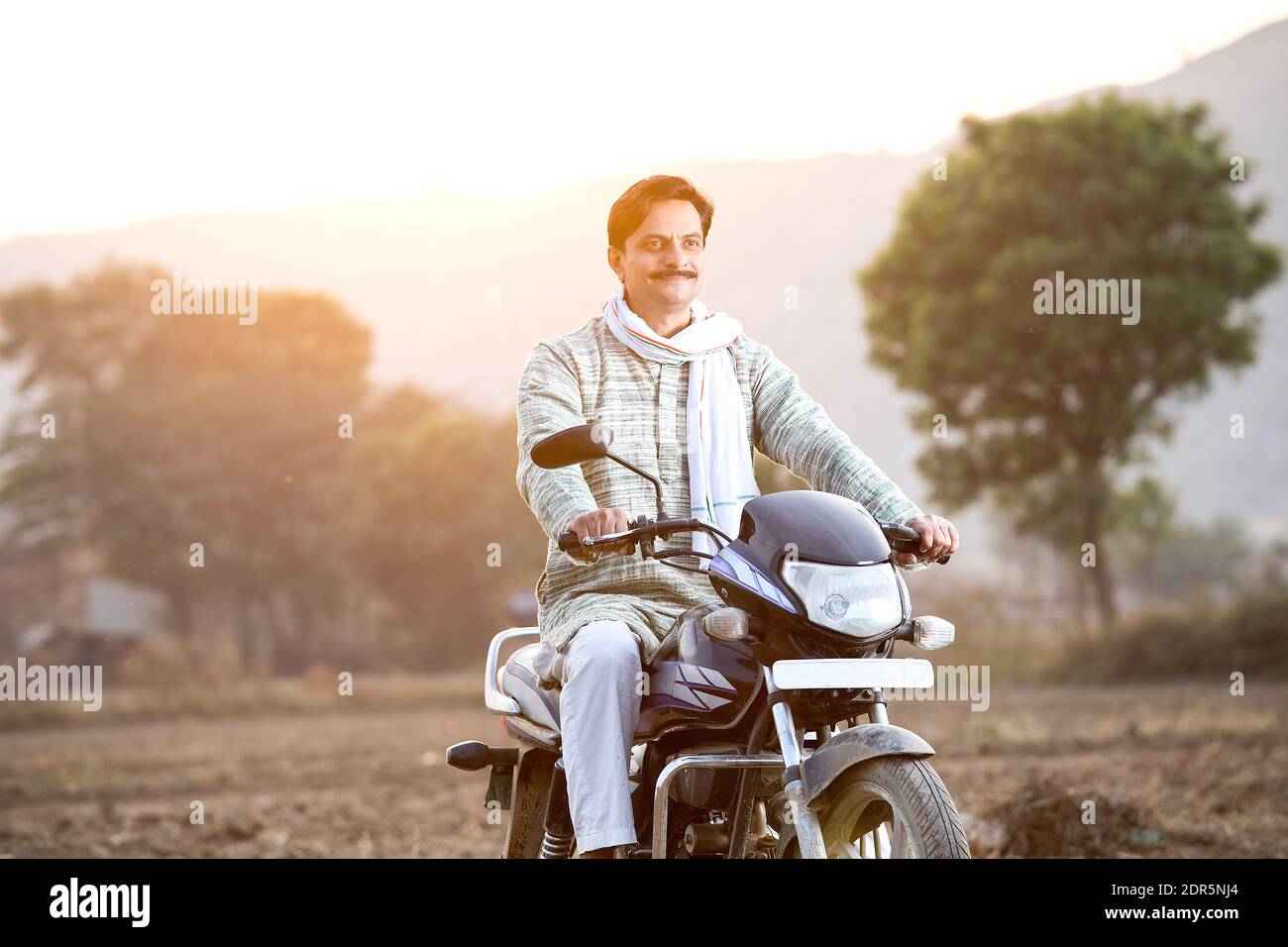 Happy rural Indian man riding on motorcycle in village Stock Photo - Alamy