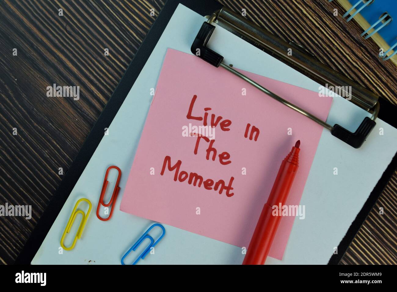 Live in The Moment write on sticky notes isolated on Wooden Table ...