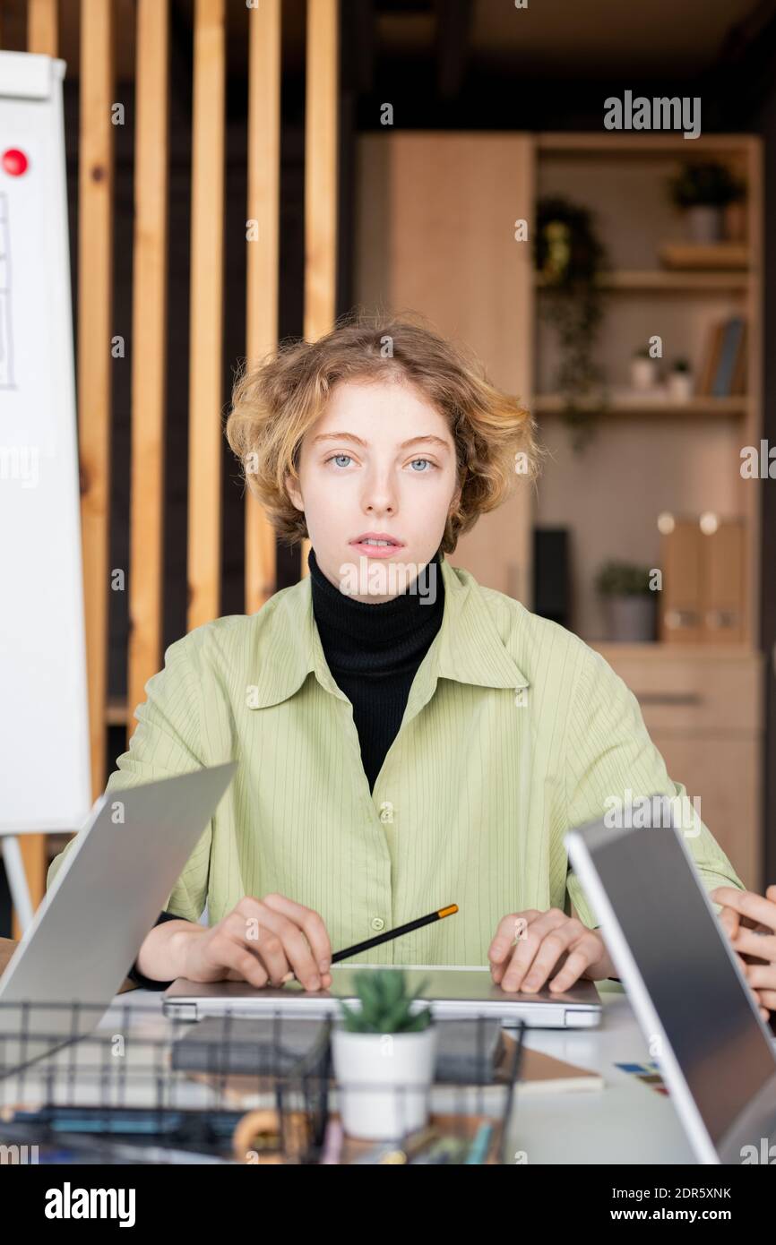 Young blond serious female mobile app developer looking at you while ...