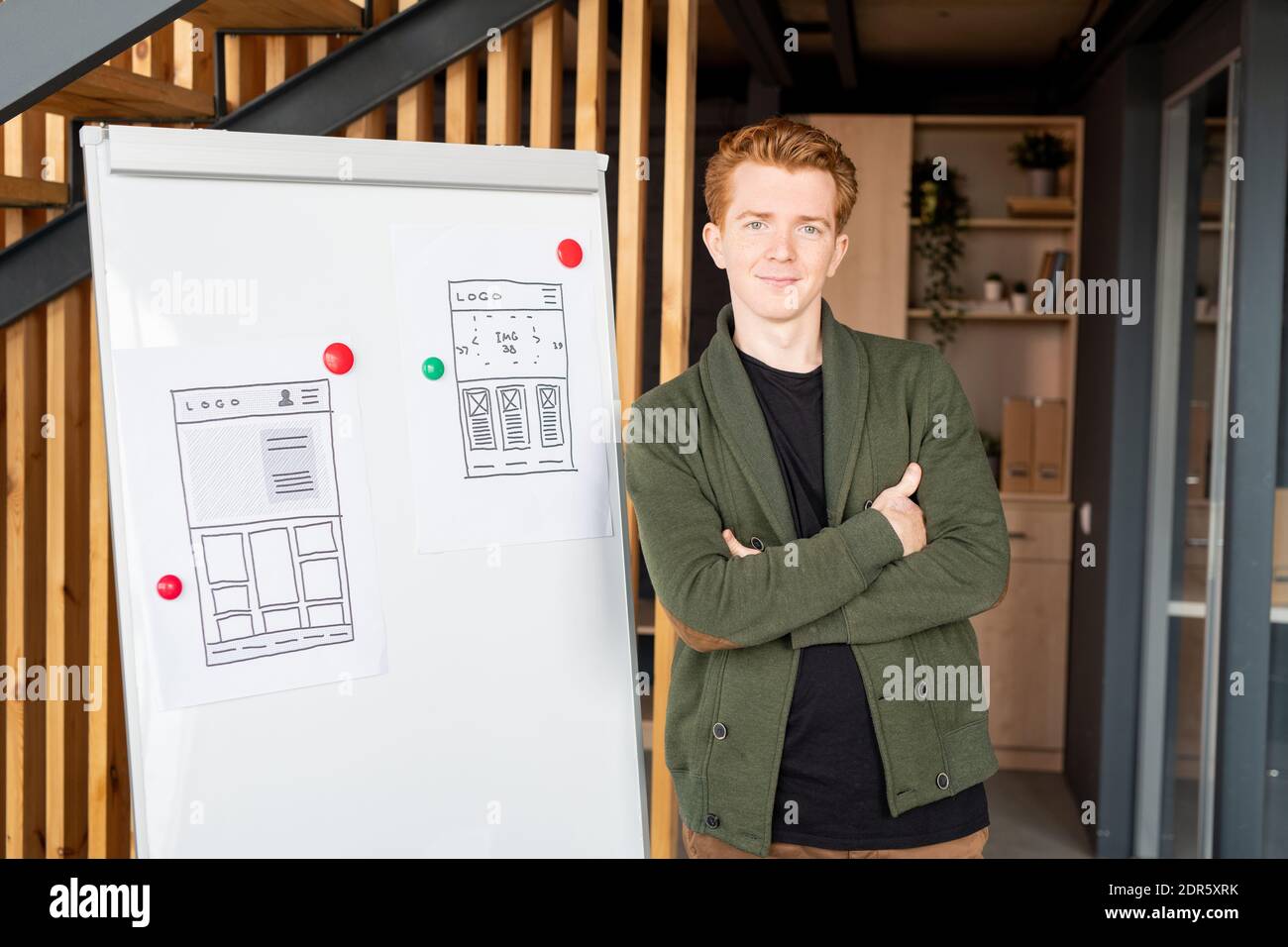 Young successful coach or mobile app developer crossing his arms by ...