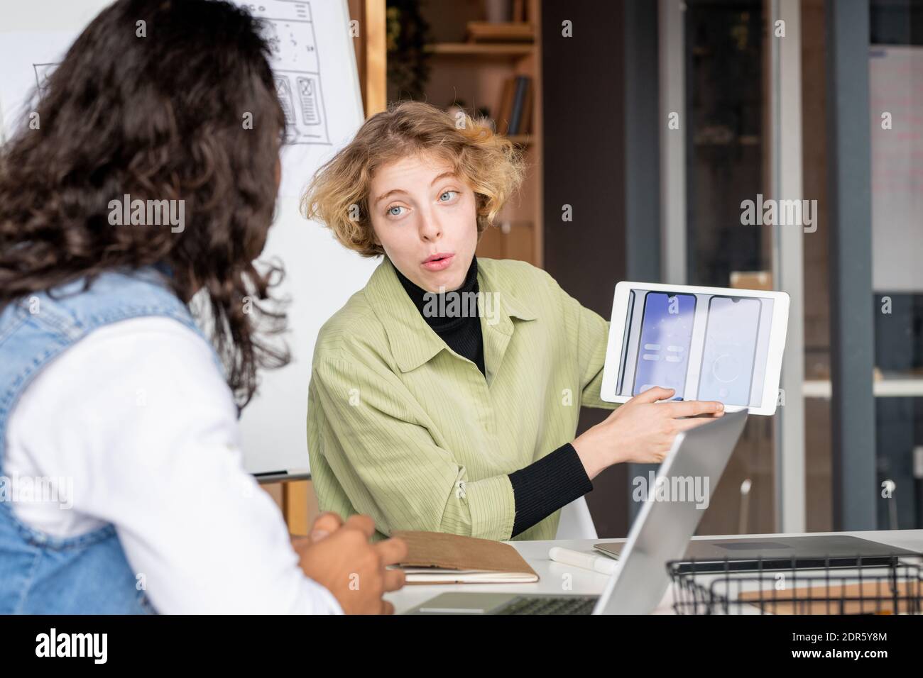 Confident young blond female mobile app developer presenting her male ...