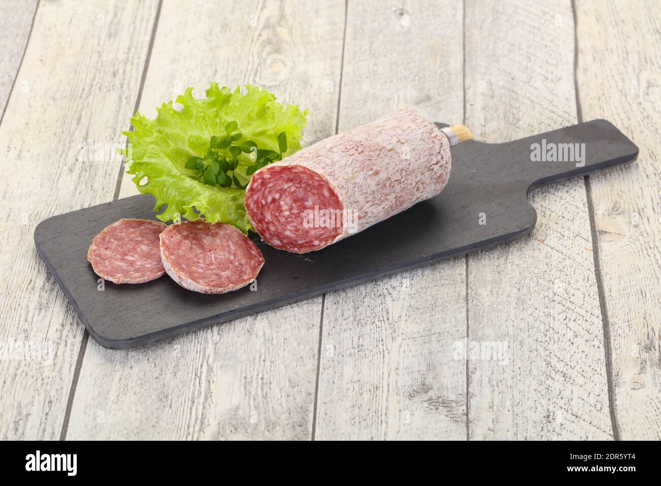 Italian dry Saliami pork sausage served salad leaves Stock Photo - Alamy
