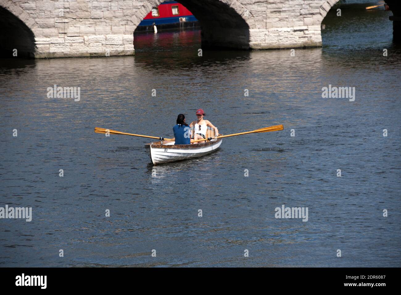 A Young Lady Rowing A Rowing Boat With Her Friend As A Passenger On The ...