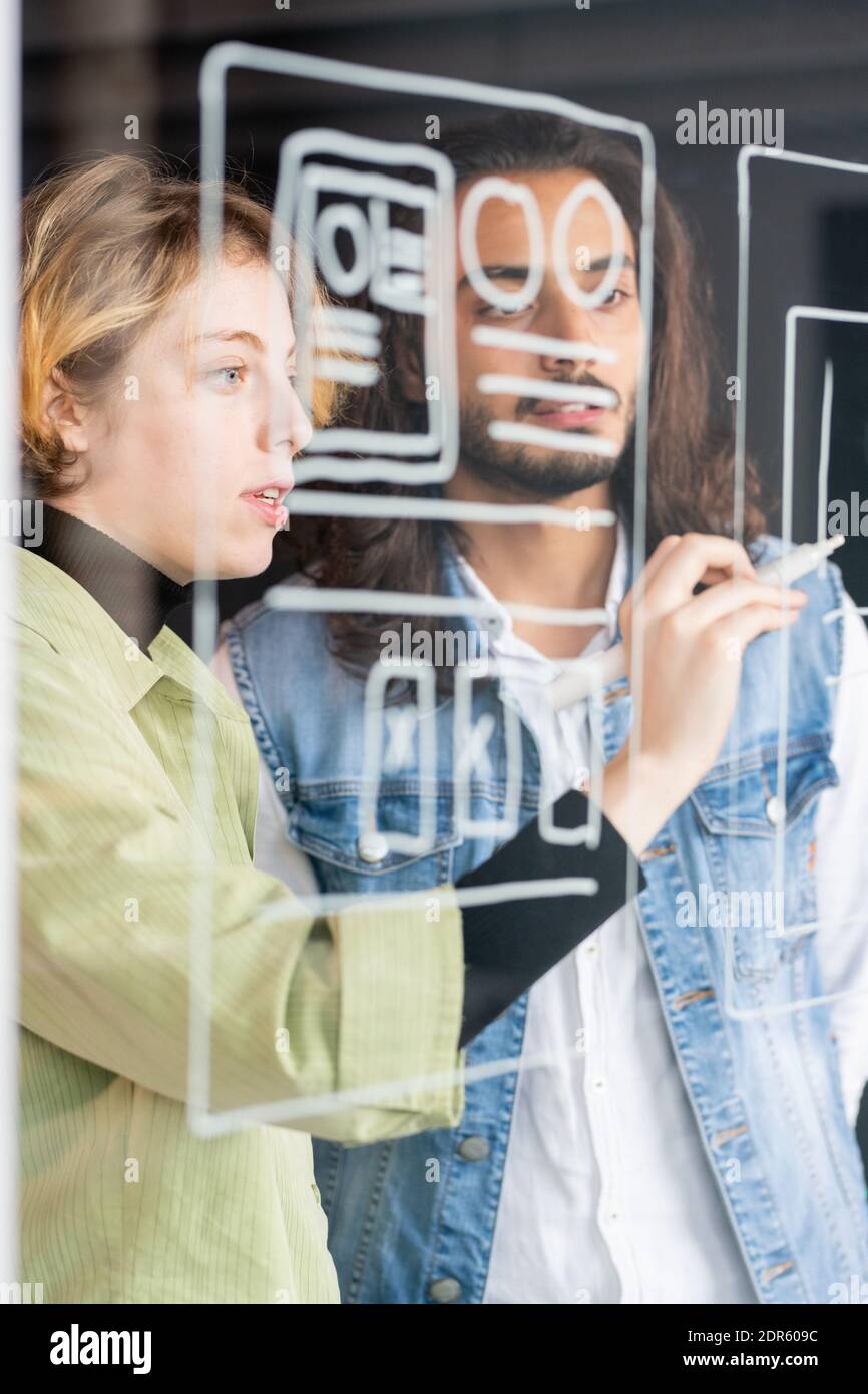 Young confident female software developer pointing at sketch of new ...