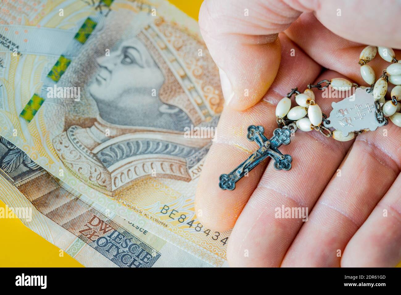 Christian rosary hand-held with money. Concept of church business and ...