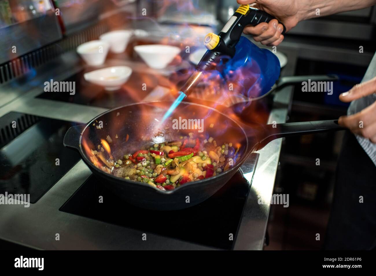 Hand of young chef using electric smoker for chopped vegetables in ...
