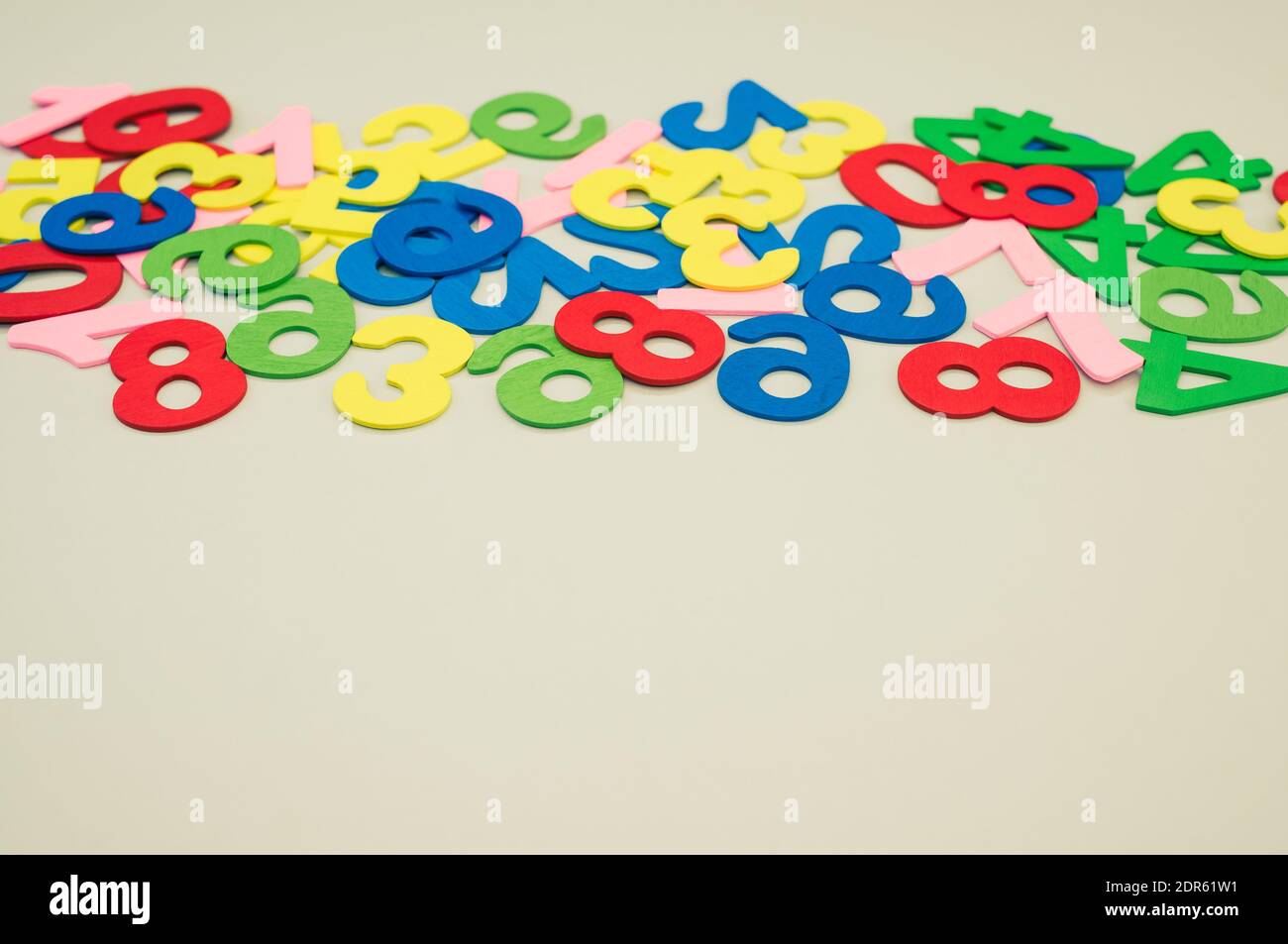 A closeup of the colorful wooden numbers scattered on a green surface ...