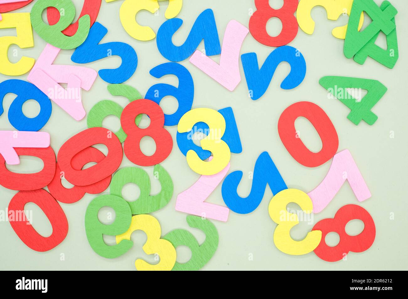 A top view of the colorful wooden numbers scattered on a green surface ...