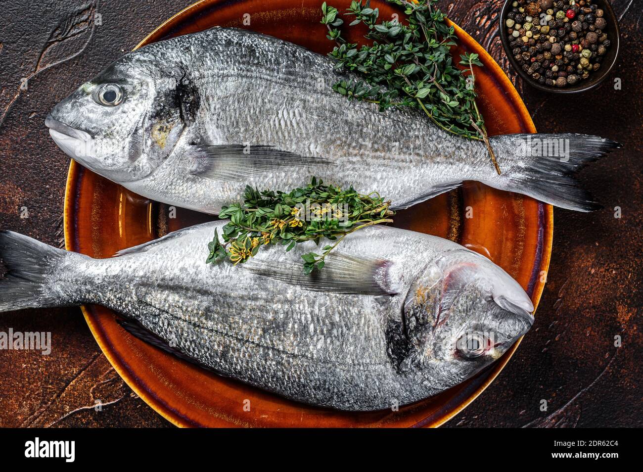 Raw Sea bream fish and ingredients for cooking. Dark background. Top ...