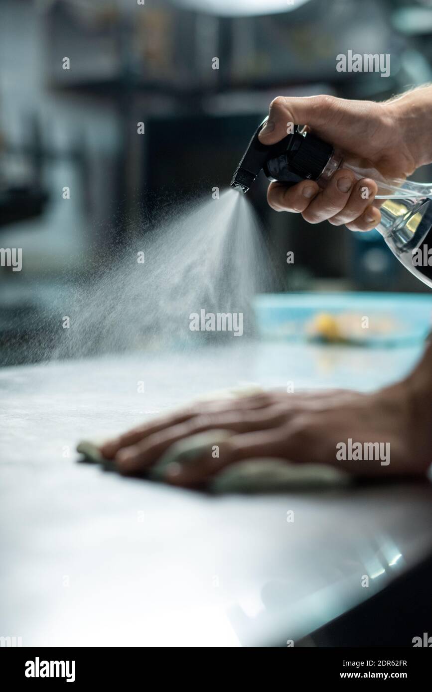 Hands of young contemporary male worker of restaurant kitchen spraying ...