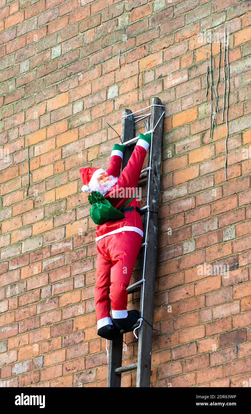 Father Christmas figure climbing a ladder Stock Photo - Alamy