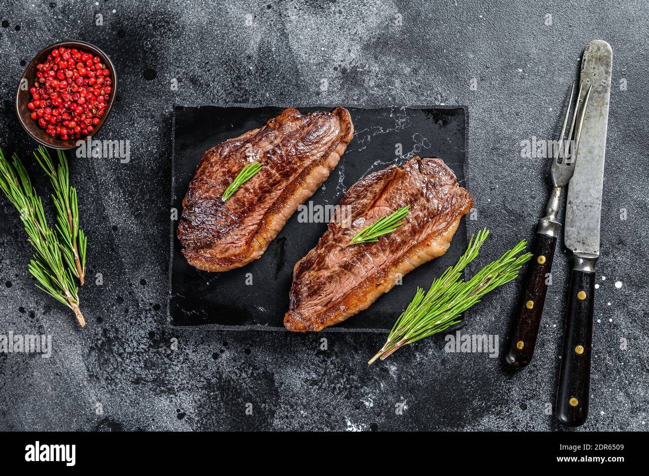 Grilled ramp cap steak on a stone chopping Board. Black background. Top ...