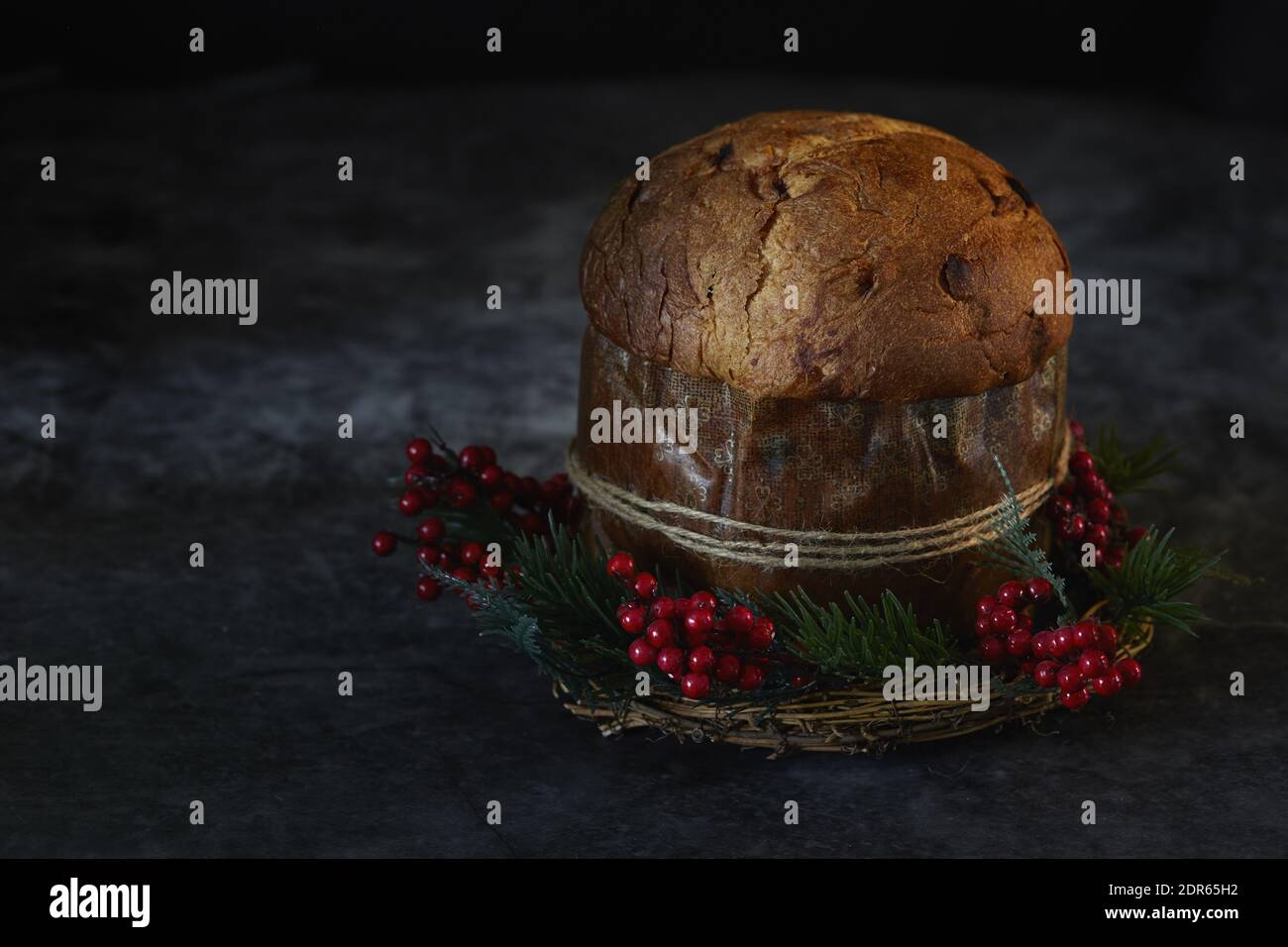 A Christmas panettone on a mistletoe wreath on a dark background Stock ...