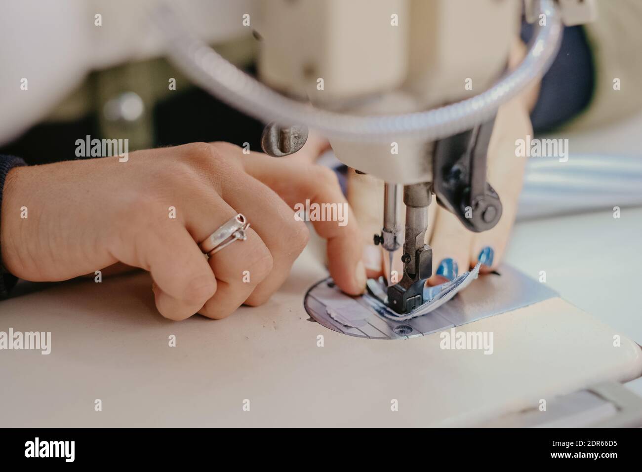 A selective focus shot of seamstress hands working on sewing machine ...