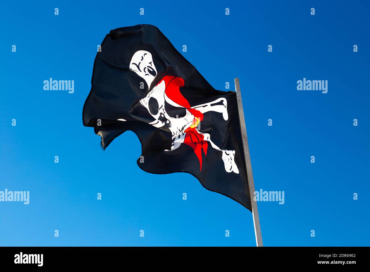 pirate flag waving in the wind against a blue sky. Marine paraphernalia ...