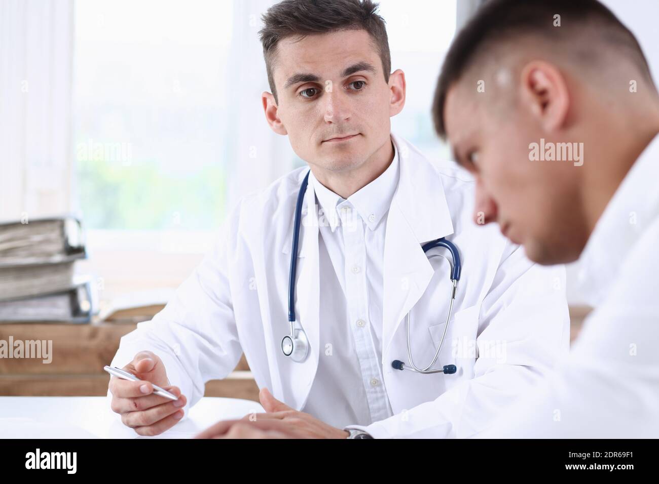 Concerned handsome doctor communicate with patient Stock Photo - Alamy