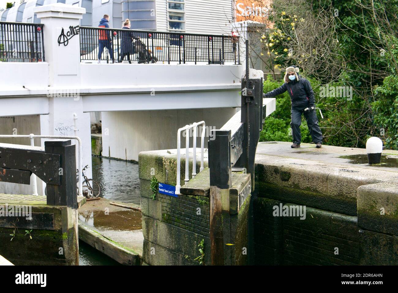 Elderly woman wearing a facemask and winter clothing opens the canal ...