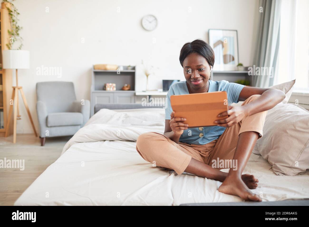 Minimal full length portrait of young African-American woman sitting on ...