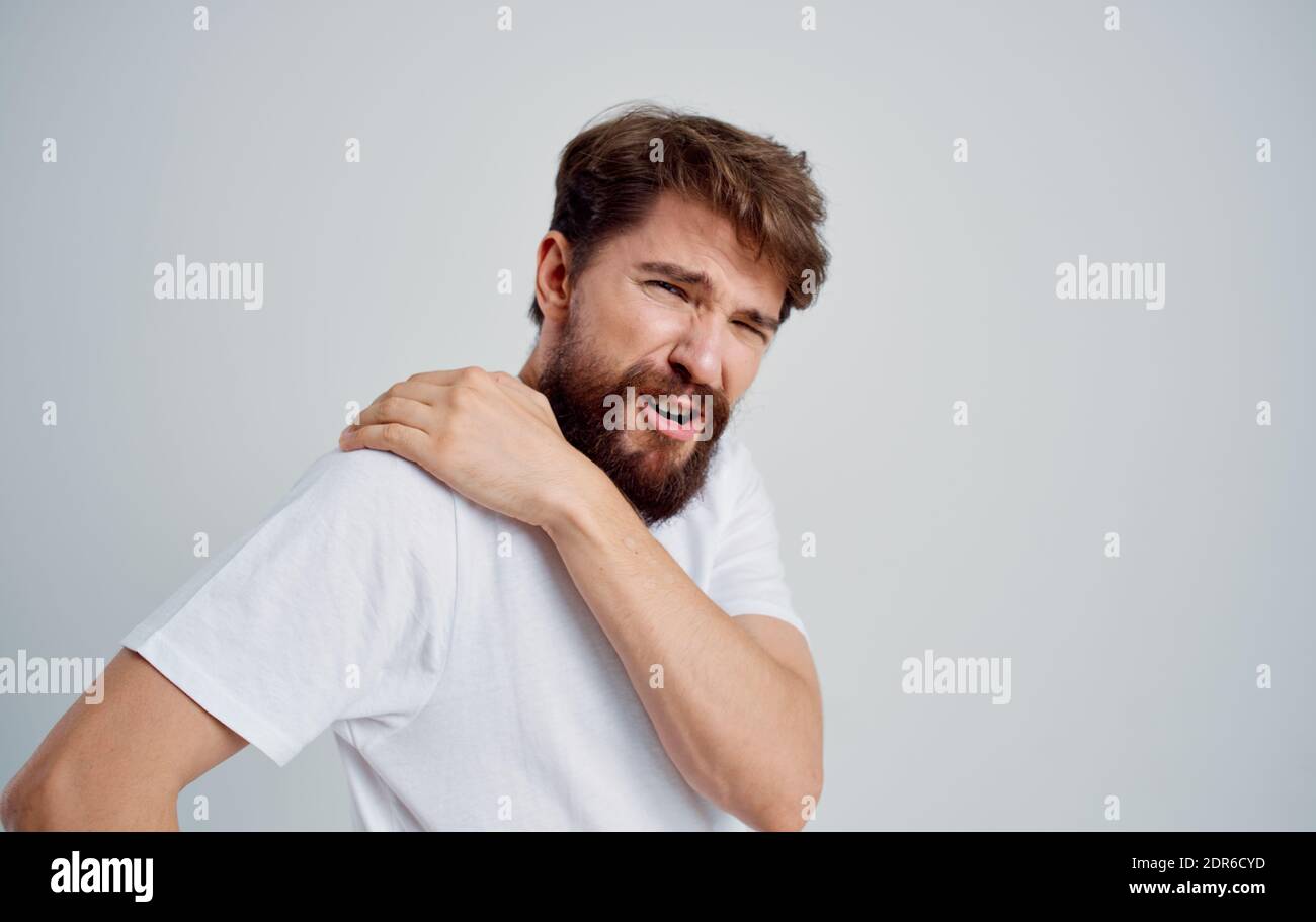 man touching shoulder with hand dislocation discomfort white t-shirt ...
