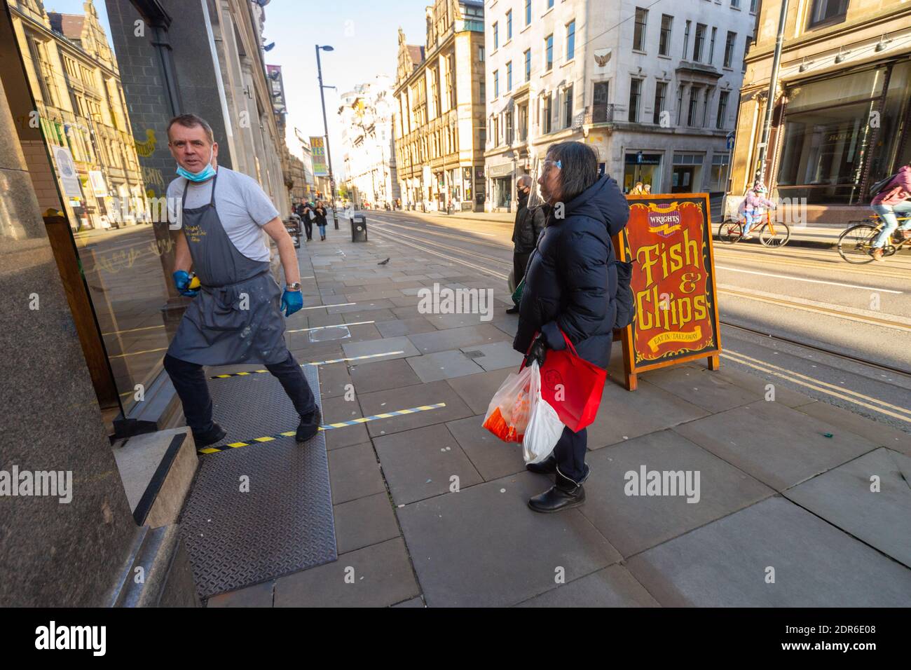 A man applies striped tape to the ground outside a chip shop in ...