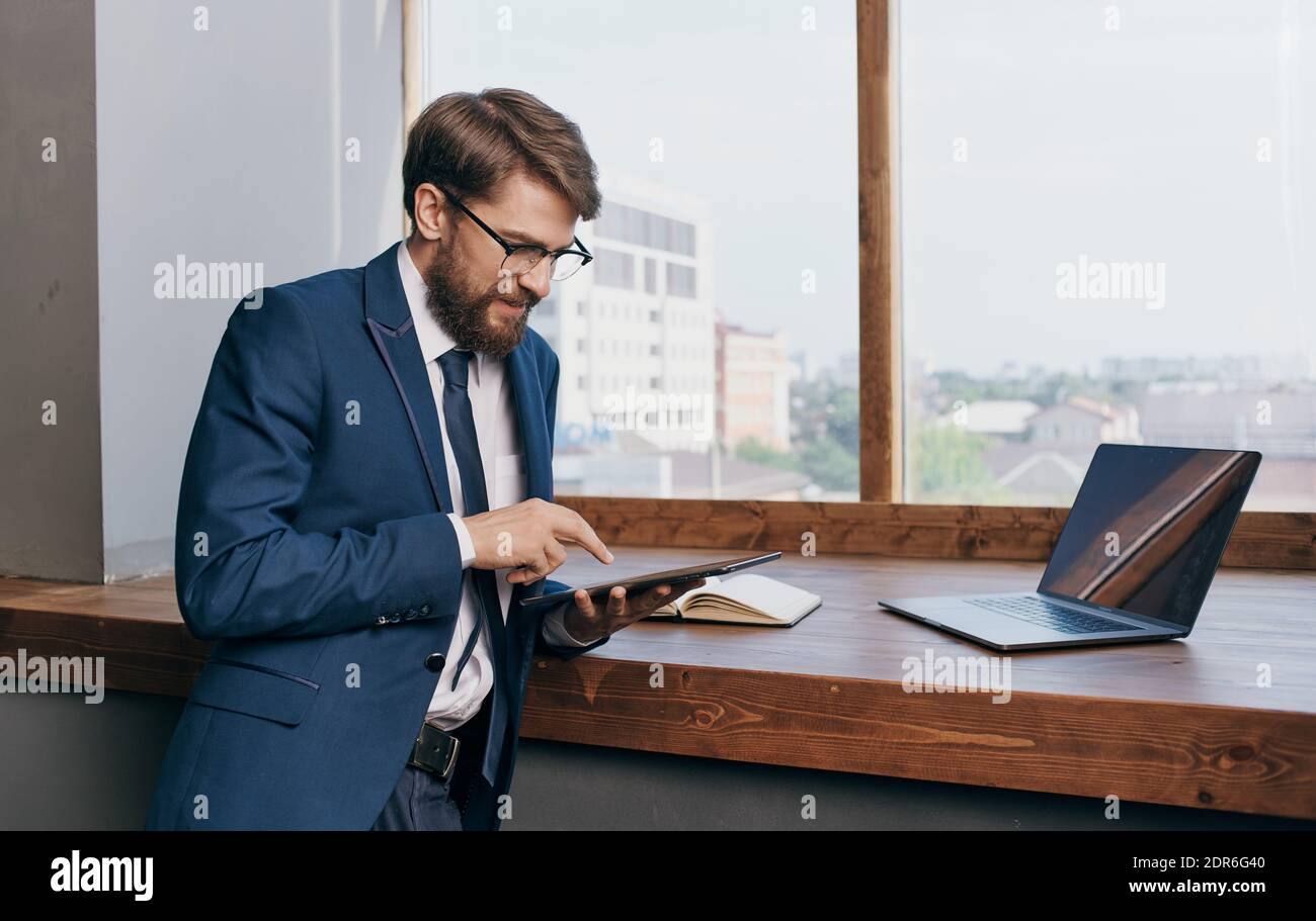 A man in a suit with a tablet in the hands of an office laptop ...